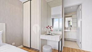 Um quarto moderno com uma cama, uma penteadeira com espelho e uma escrivaninha com cadeira.