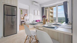 Uma cozinha moderna com geladeira embutida, área de refeições com cadeiras brancas e uma grande janela com vista para a cidade.