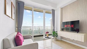 Uma sala de estar moderna com uma TV grande, um sofá, uma mesa de centro e uma varanda com vista.
