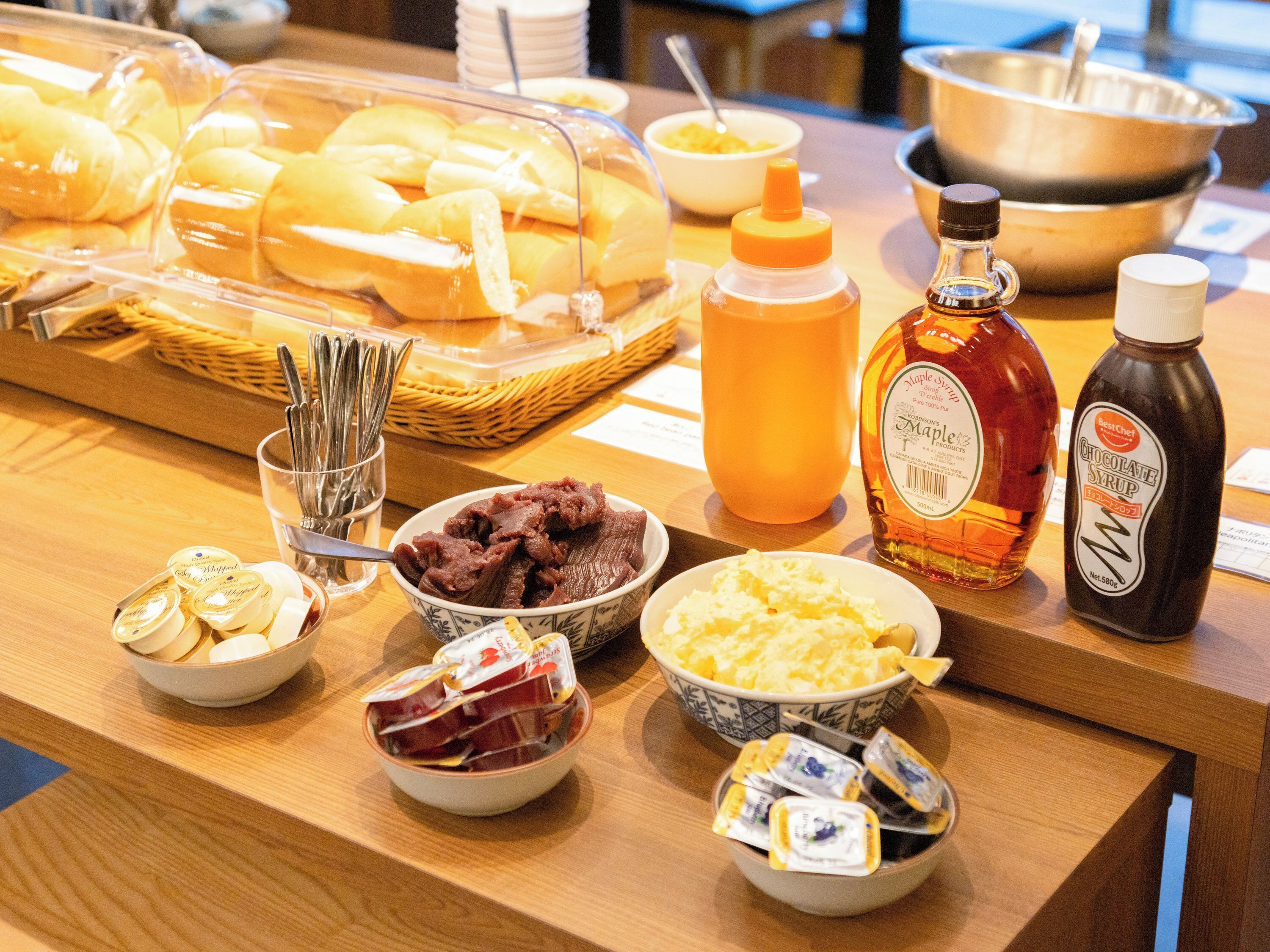 Um buffet de café da manhã com diversas opções de alimentos e acompanhamentos.
