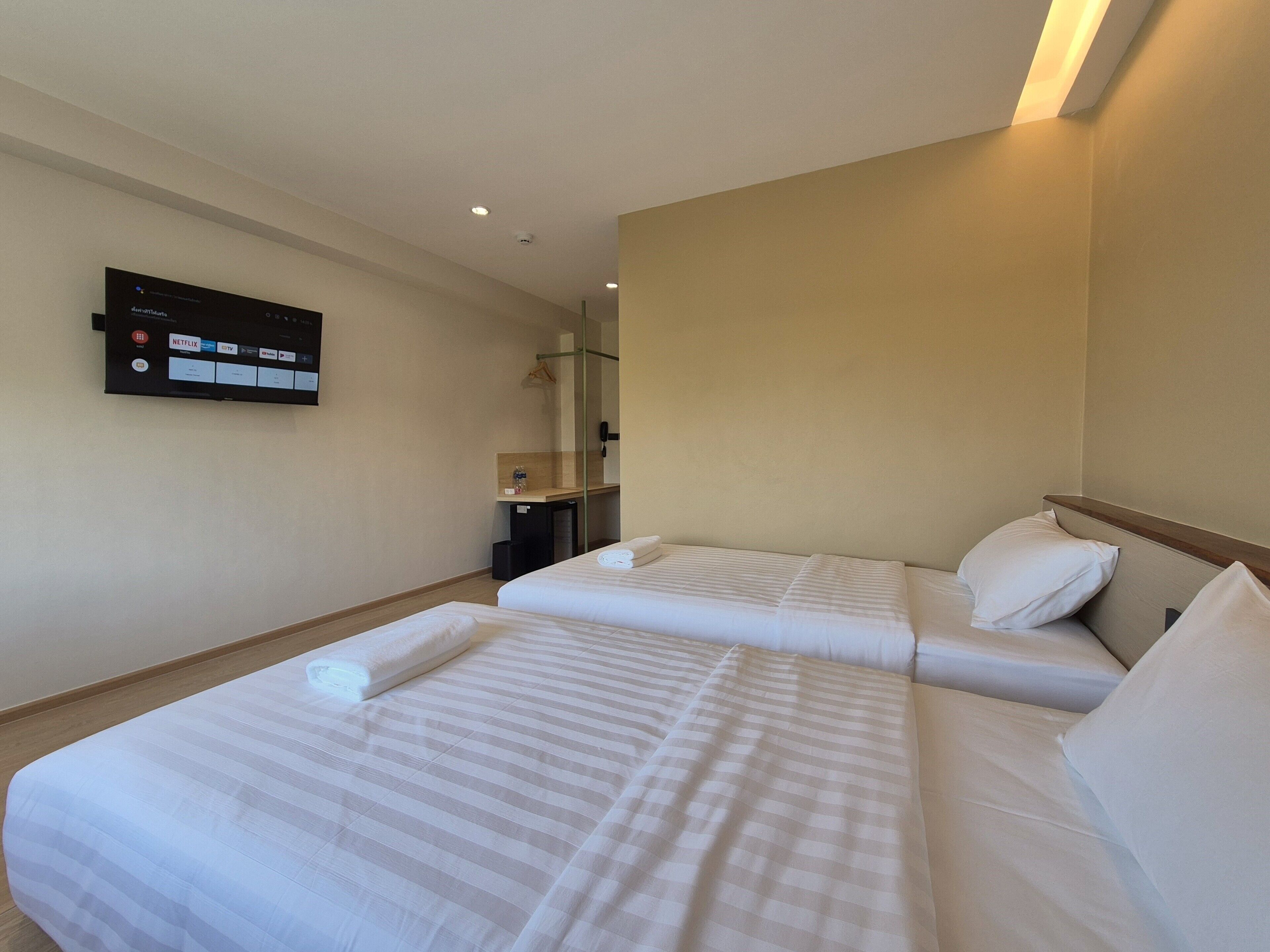 Quarto de hotel com duas camas, uma televisão fixada na parede e uma pequena escrivaninha com espelho.