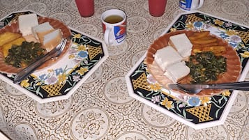 Uma mesa de jantar com dois pratos de comida, duas xícaras de chá e uma caneca.