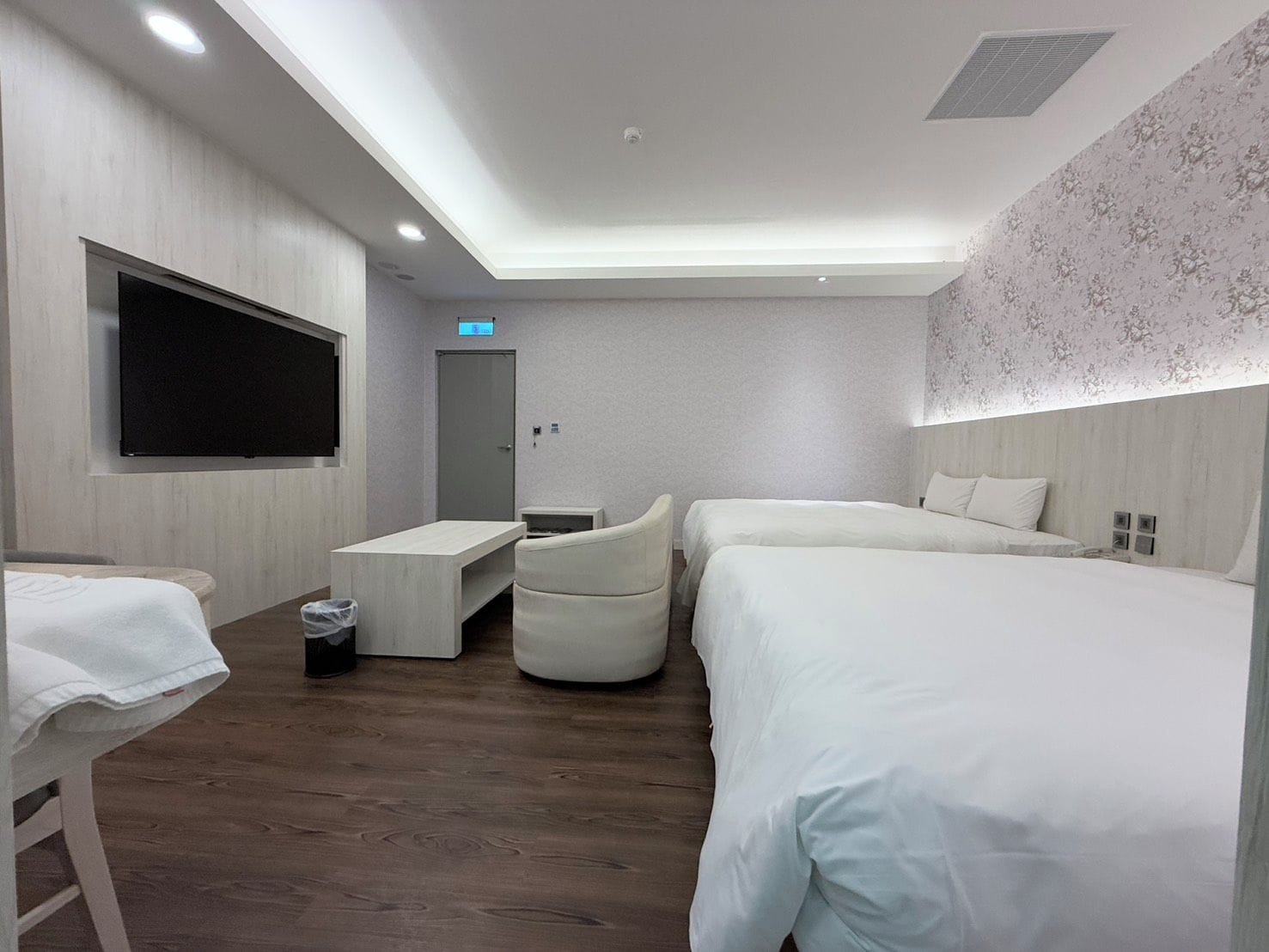 Quarto de hotel com televisão de tela plana, escrivaninha, duas camas e um pequeno espaço de estar.