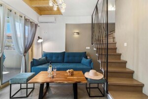 Uma sala de estar moderna com um sofá azul, uma mesa de centro de madeira e uma escada.