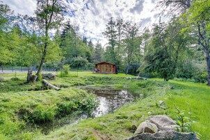 Uma cabana rodeada por vegetação exuberante e um pequeno lago.