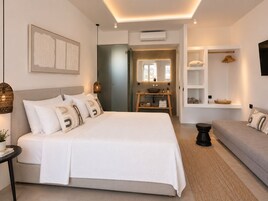 Quarto moderno com uma cama grande, mesas de cabeceira, guarda-roupa embutido e um banheiro visível através de uma porta aberta.