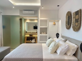 Quarto moderno com uma cama grande, mesa de cabeceira, espelho e televisão presa à parede.