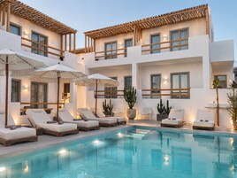 Um hotel moderno com piscina, várias varandas e espreguiçadeiras.