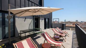 Terraço no telhado com cadeiras de estar, uma mesa e um guarda-sol.