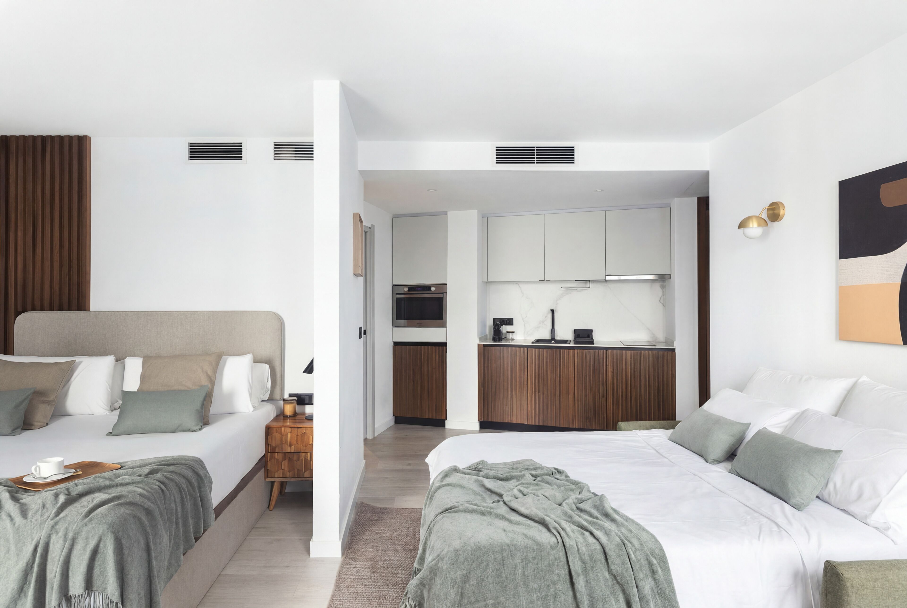 Quarto de hotel moderno com duas camas, uma kitchenette e um banheiro.