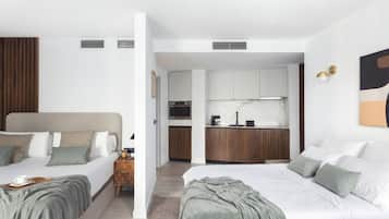 Quarto de hotel moderno com duas camas, uma kitchenette e um banheiro.