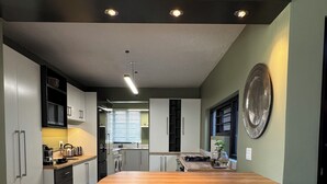 Cozinha moderna com ilha central, banquetas e vista para a sala de jantar.