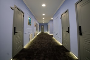 Corredor com portas brancas, piso coberto de carpete e iluminação embutida.