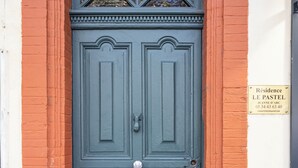 Uma porta dupla com uma placa de identificação, uma placa comemorativa e uma pequena janela acima.
