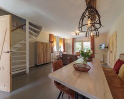 Cozinha espaçosa com mesa de madeira, cadeiras e luminária pendente.