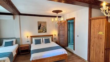 Quarto com duas camas, guarda-roupa de madeira, um candelabro e um quadro na parede.