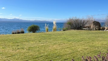 Um campo gramado com vista para um corpo d'água e montanhas ao longe.