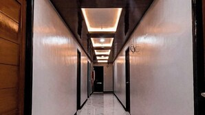 Um corredor comprido e estreito com piso de mármore polido e iluminação embutida.