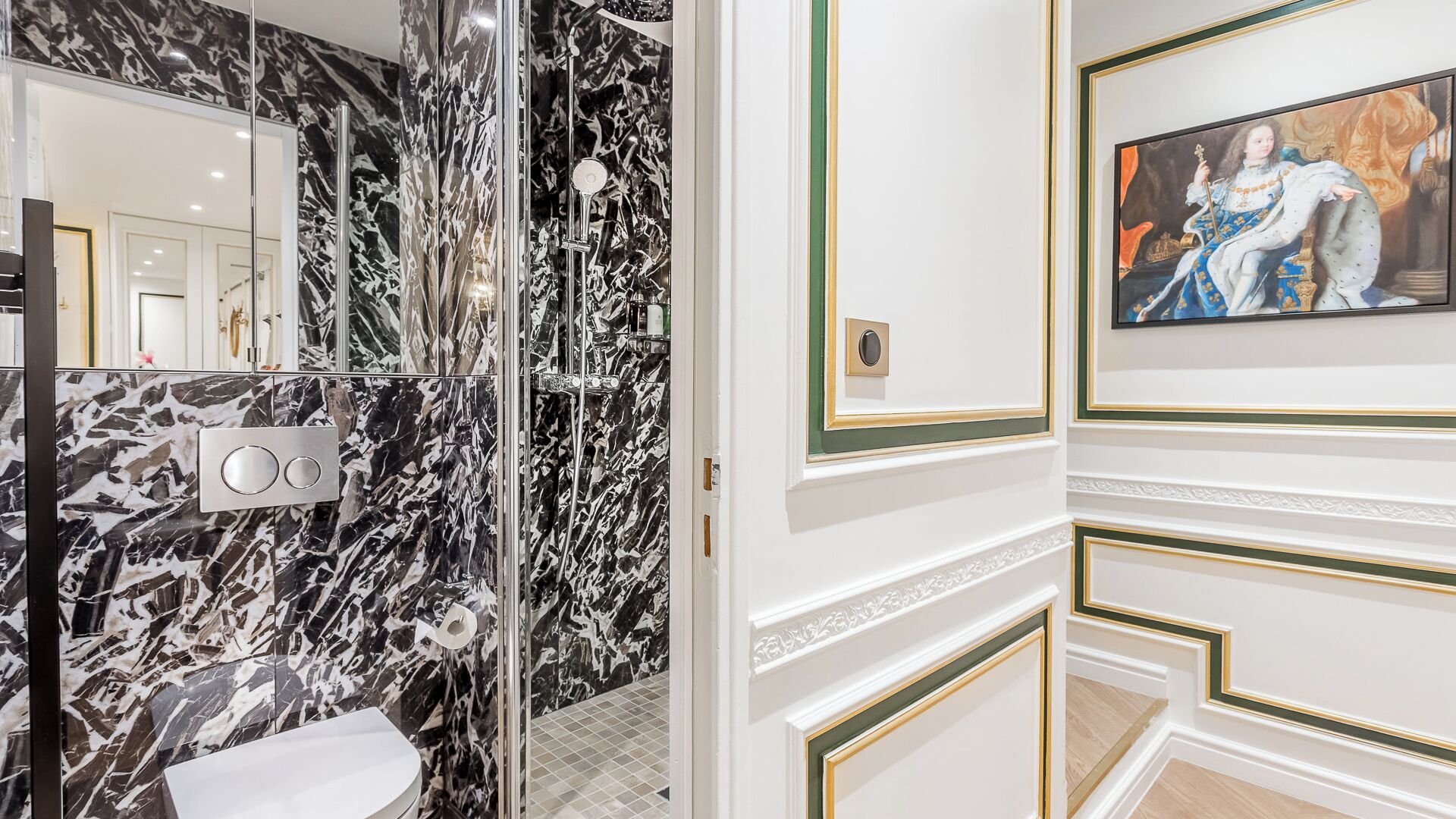 Uma casa de banho luxuosa com paredes de mármore, cabine de duche em vidro, lavatório branco e um quadro emoldurado na parede.