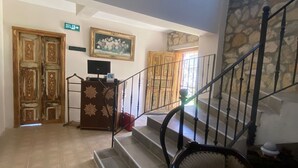 Uma escadaria leva a um patamar com uma parede de pedra e uma porta de madeira.