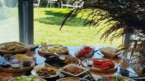 Mesa de buffet com diversos alimentos e vista para um jardim lá fora.