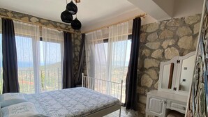 Um quarto com uma cama, cômoda, espelho e parede de pedra.