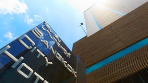 Um edifício moderno com fachada refletora e as palavras "HOTEL" e "CITY HOTEL" em destaque.