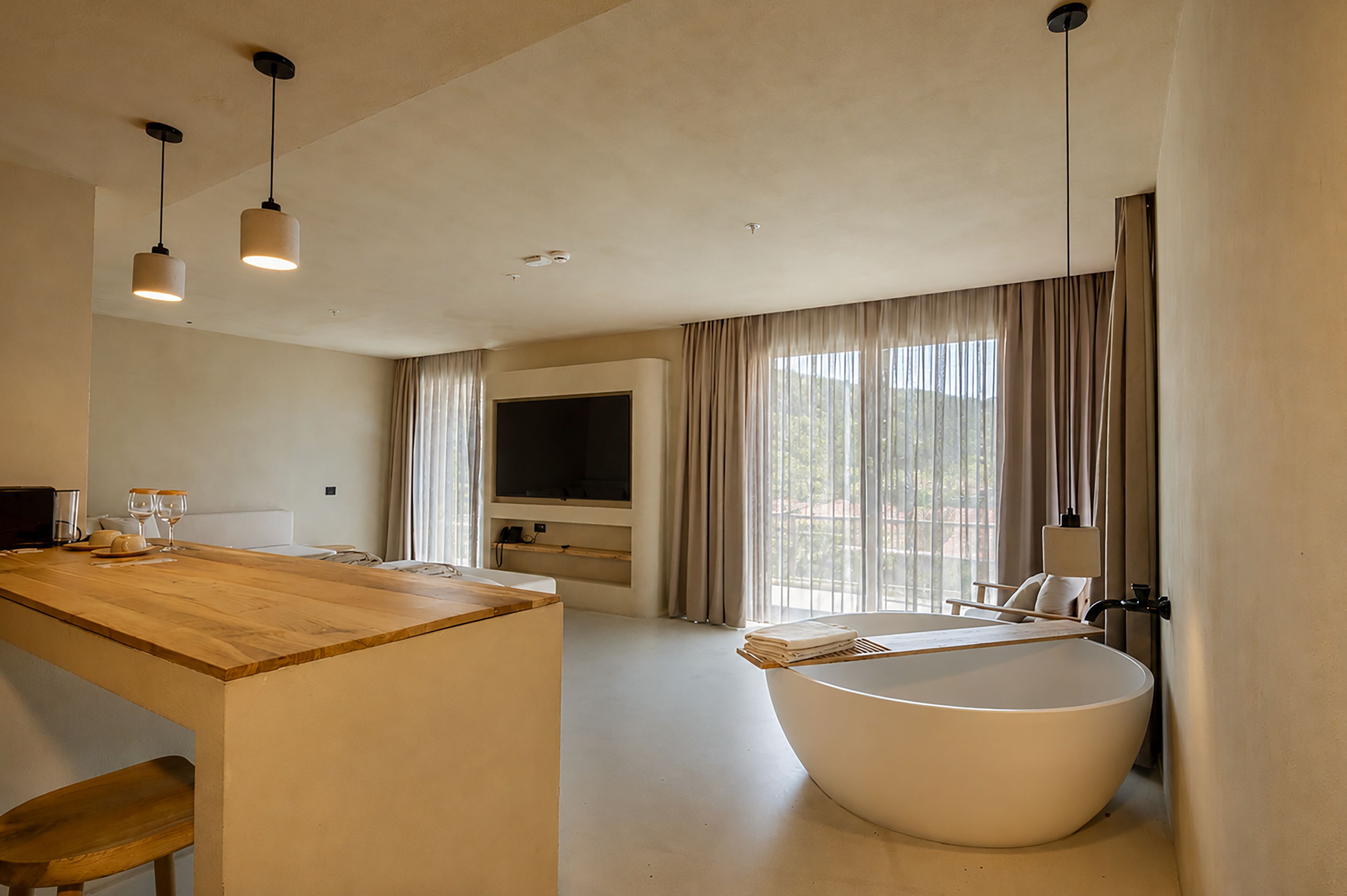Uma casa de banho moderna com uma banheira independente, um lavatório de madeira e uma janela grande com cortinas.