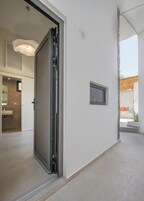 Um interior moderno com uma porta deslizante para um banheiro, uma luminária embutida no teto e uma pequena janela com vista para o exterior.
