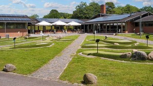 Edifício com painéis solares, área de estar externa e jardim ajardinado com um caminho.