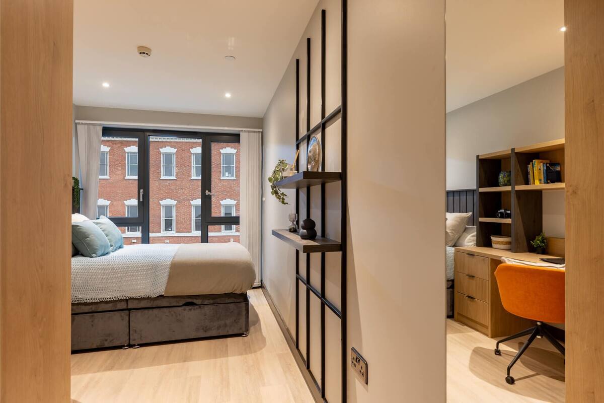Um quarto moderno com uma janela grande, uma cama, uma escrivaninha e uma estante.