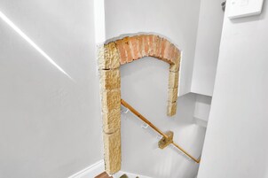 Canto de um quarto com um arco de tijolos em construção e uma viga de madeira.