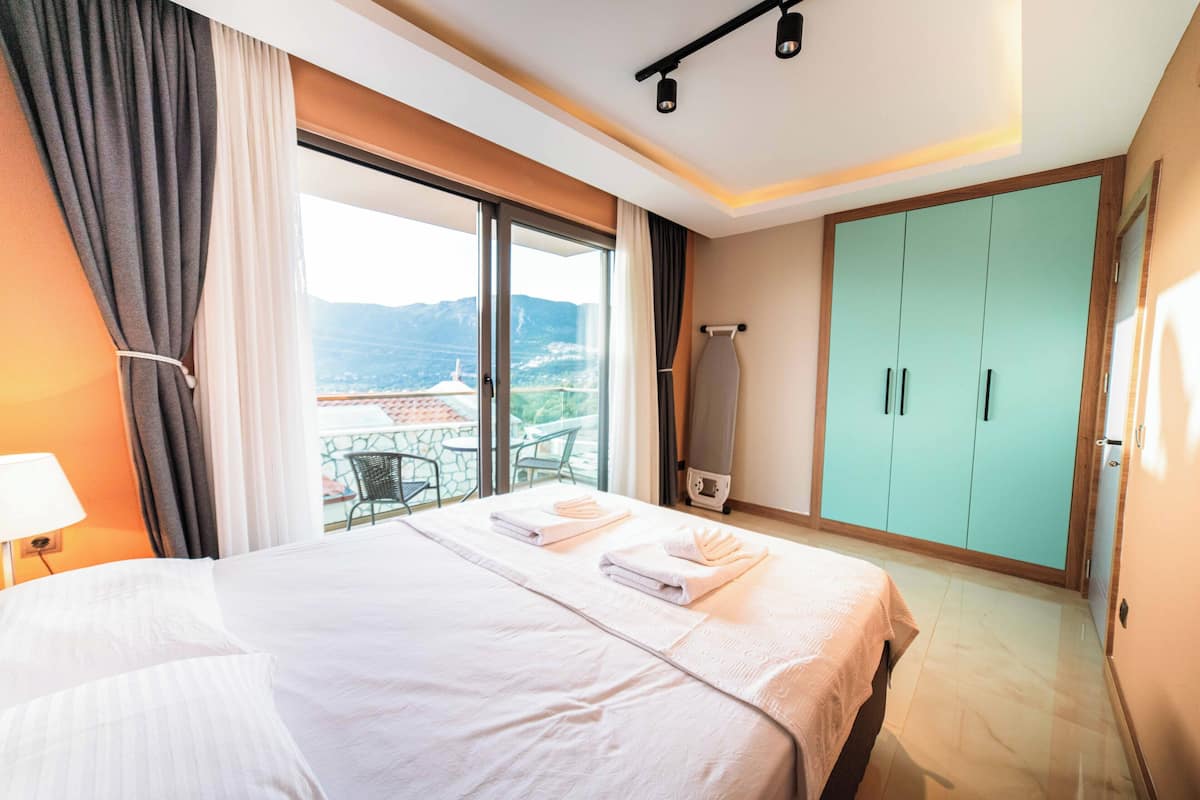 Quarto de hotel com uma cama grande, varanda com vista e guarda-roupa.