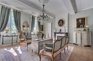 Quarto com lustre, duas cadeiras, uma mesa, lareira e um armário.