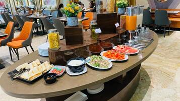 Disposição de buffet com diversos alimentos e um dispensador de sucos.