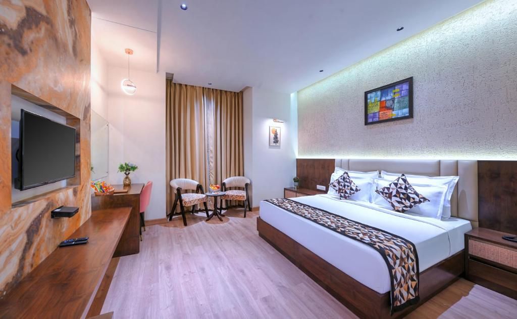 Quarto de hotel com uma cama grande, televisão, escrivaninha e uma cadeira.