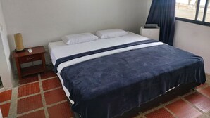 Quarto com cama, mesa de cabeceira, luminária, quadro e janela com cortinas.