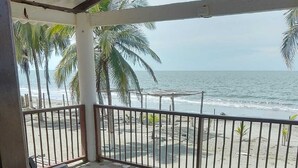 Uma área de estar coberta ao ar livre com vista para a praia e o oceano.