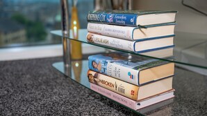 Livros empilhados em uma estante de vidro.