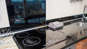 Cozinha com fogão preto, pia de aço inoxidável e janela com vista para a cidade.
