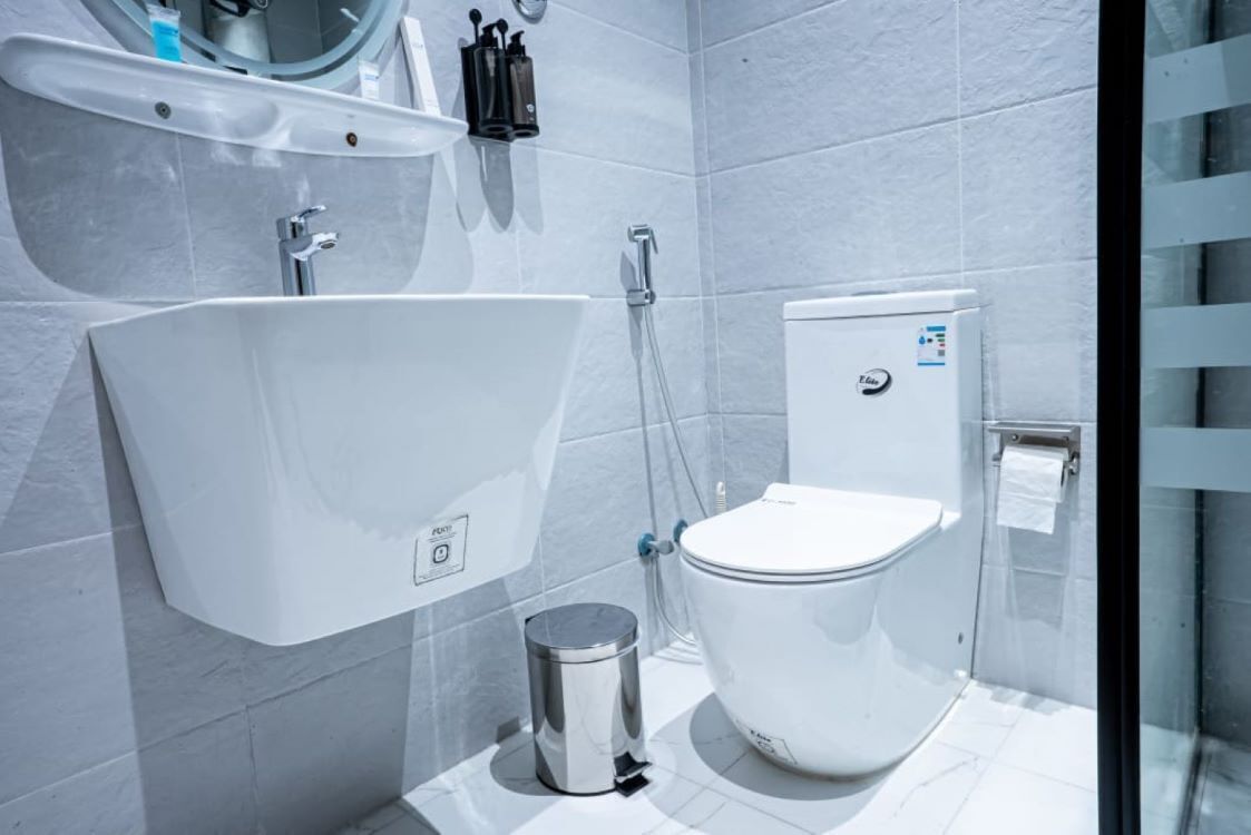 Uma casa de banho moderna com uma banheira independente, sanita e um contentor de lixo.