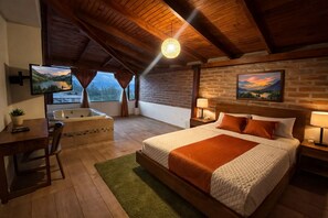 Quarto com uma cama grande, uma escrivaninha, uma cadeira, uma banheira e uma televisão.