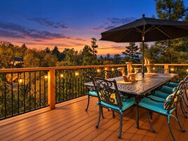 Um deck de madeira com mesa, cadeiras, um guarda-sol e corrimão.