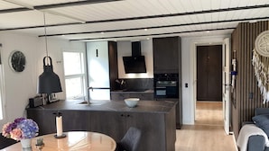 Uma cozinha moderna com uma ilha central, uma área de refeições com mesa redonda e um espaço de estar com sofá.