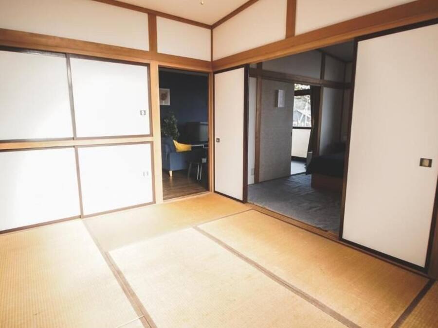 Um quarto japonês tradicional com tatame, portas deslizantes e vista para uma varanda externa.