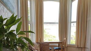 Uma sala de estar aconchegante com um sofá estampado, uma mesa de centro de madeira e uma grande planta em vaso.