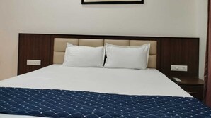 Quarto de hotel com uma cama grande, cabeceira, quadro na parede e mesa de cabeceira.