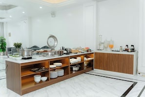 Cozinha moderna com bancada de mármore, prateleiras de madeira e diversos eletrodomésticos.