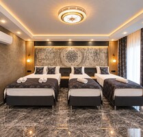Quarto de hotel com duas camas, um mural grande na parede e um lustre moderno.