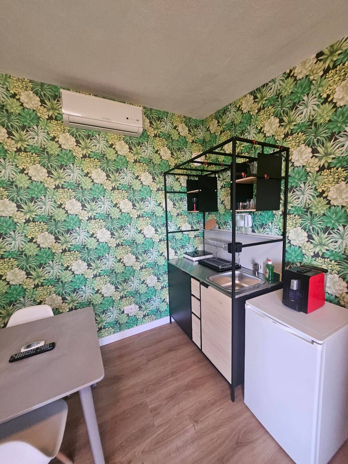 Uma cozinha compacta com geladeira embutida, uma pia pequena e uma máquina de café.
